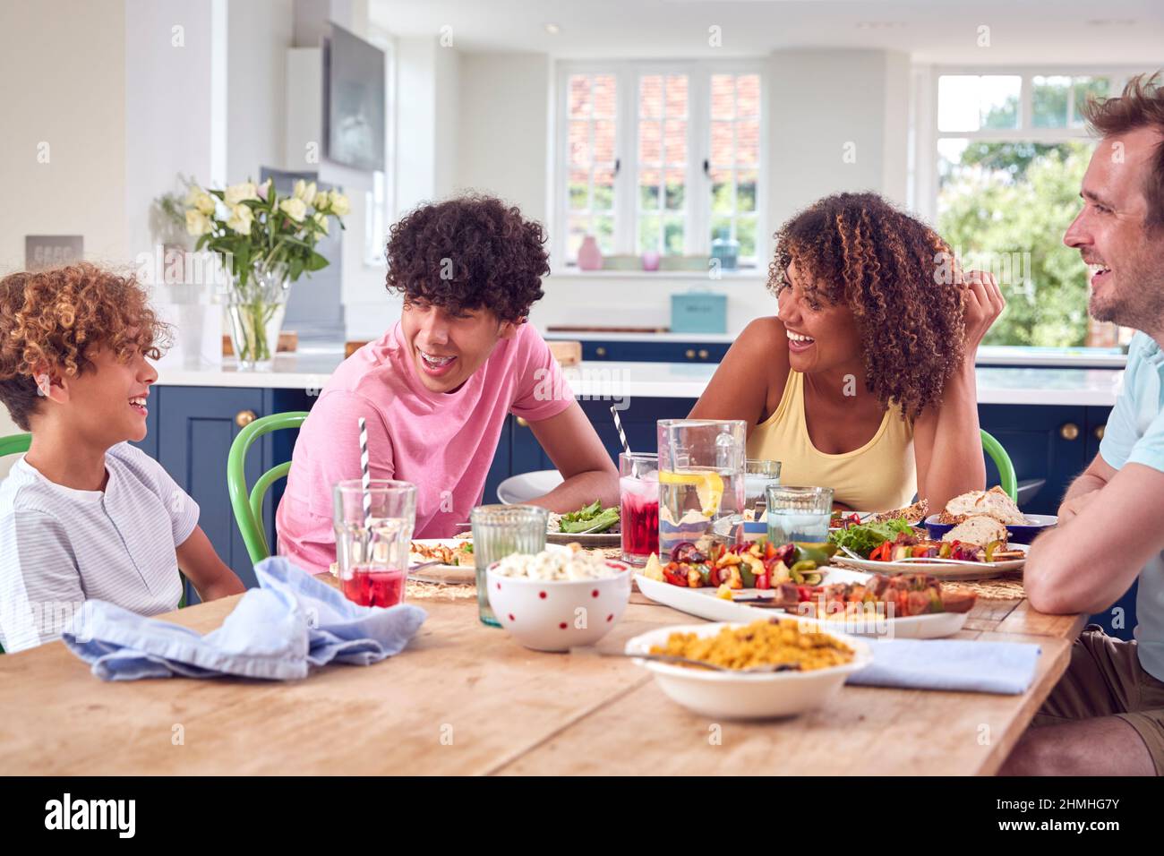Family Sitting Around Table At Home Eating Meal Together Stock Photo ...