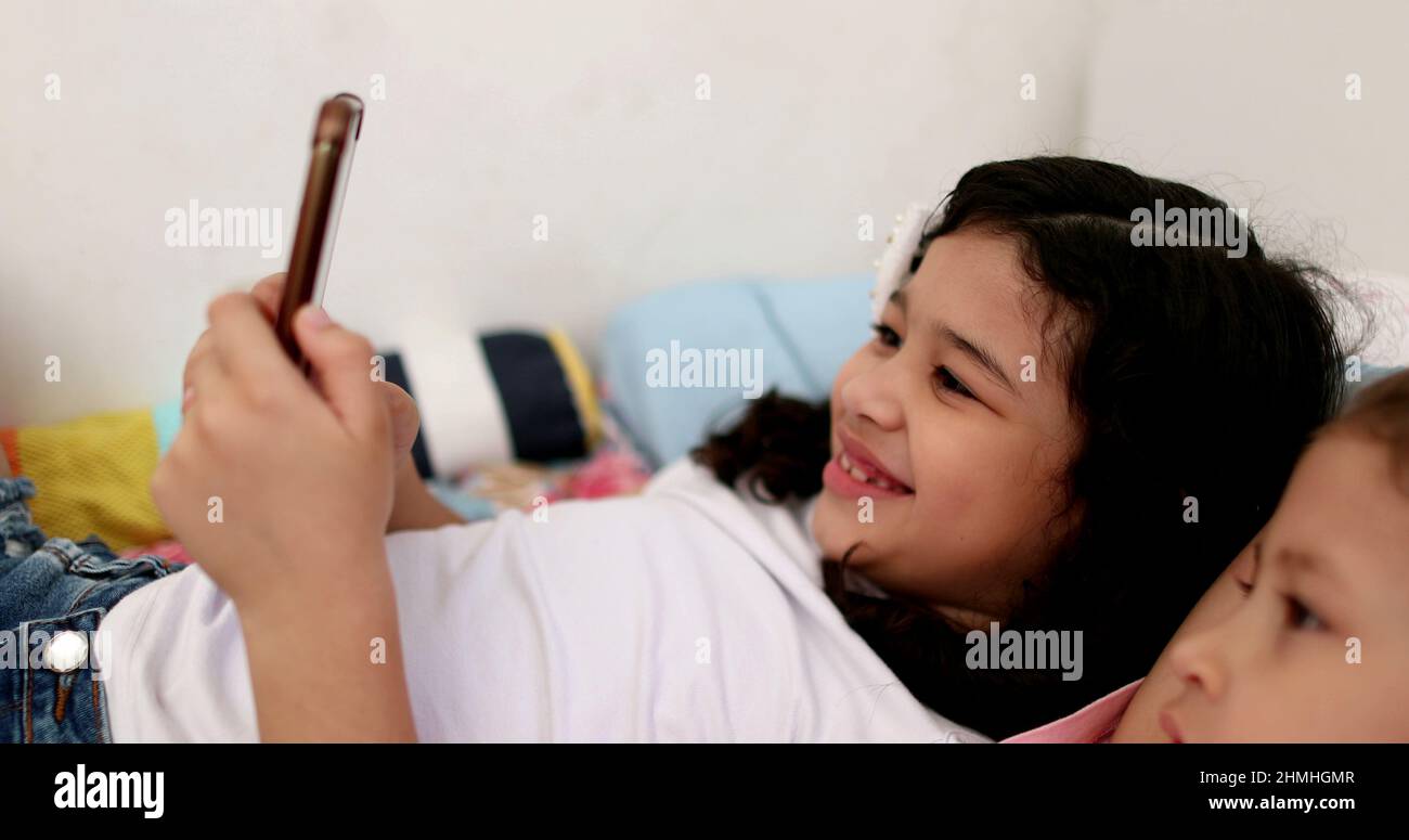 Female children siblings using cellphone Stock Photo - Alamy