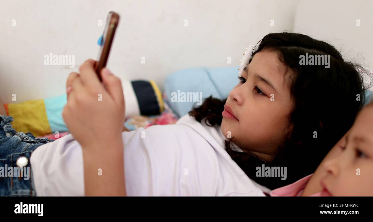 Female children siblings using cellphone Stock Photo - Alamy