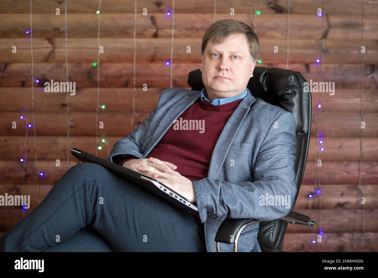 An adult blond man in a strict gray jacket is sitting in a leather ...