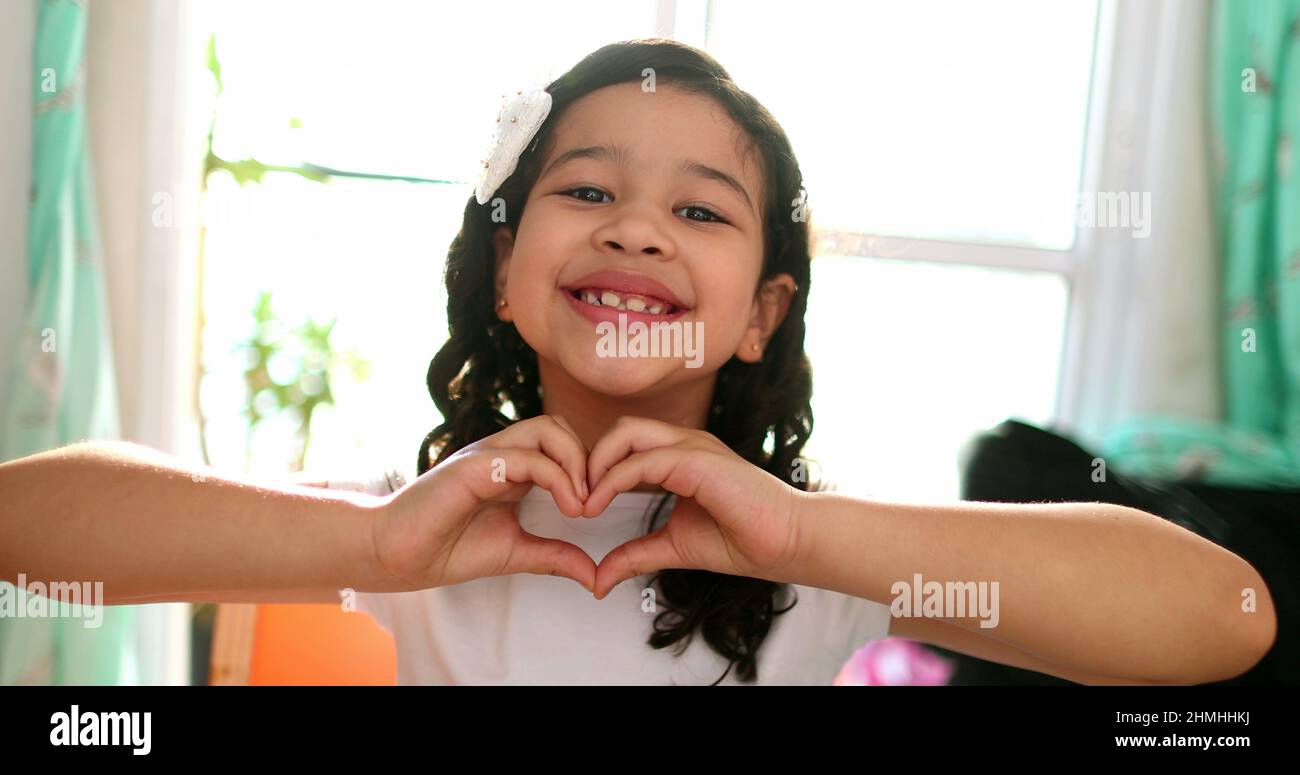 Mixed race girl child doing heart sign with hands Stock Photo - Alamy
