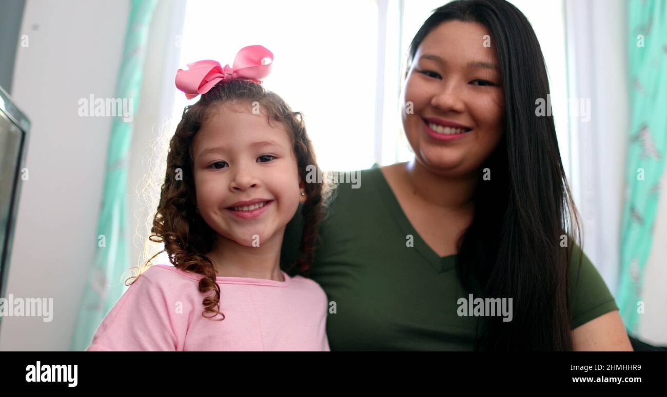 MIxed race mother and child girl smiling at camera, ethnically diverse parent and kid daughter ...