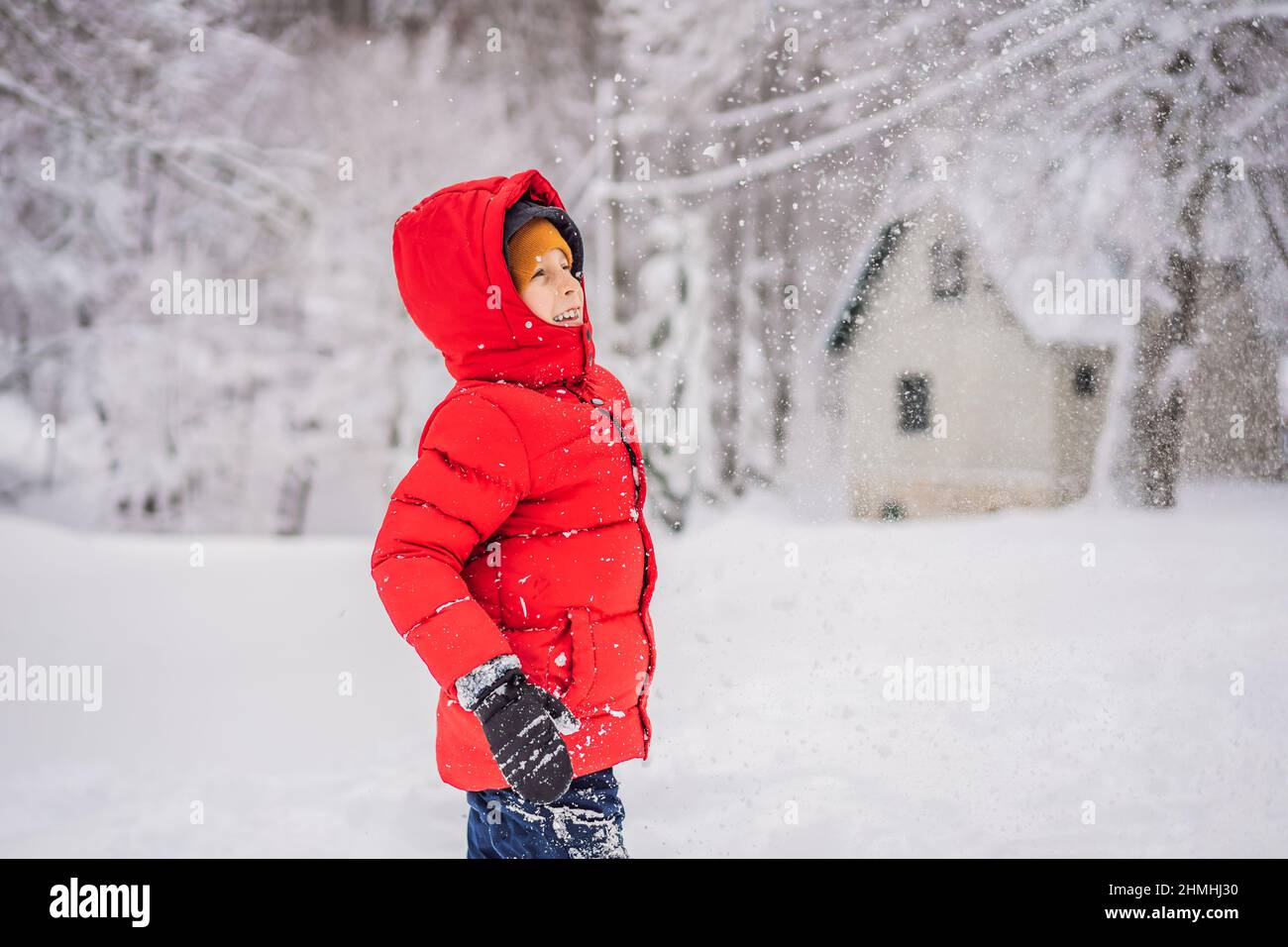 Funny little boy in blue winter clothes walks during a snowfall ...