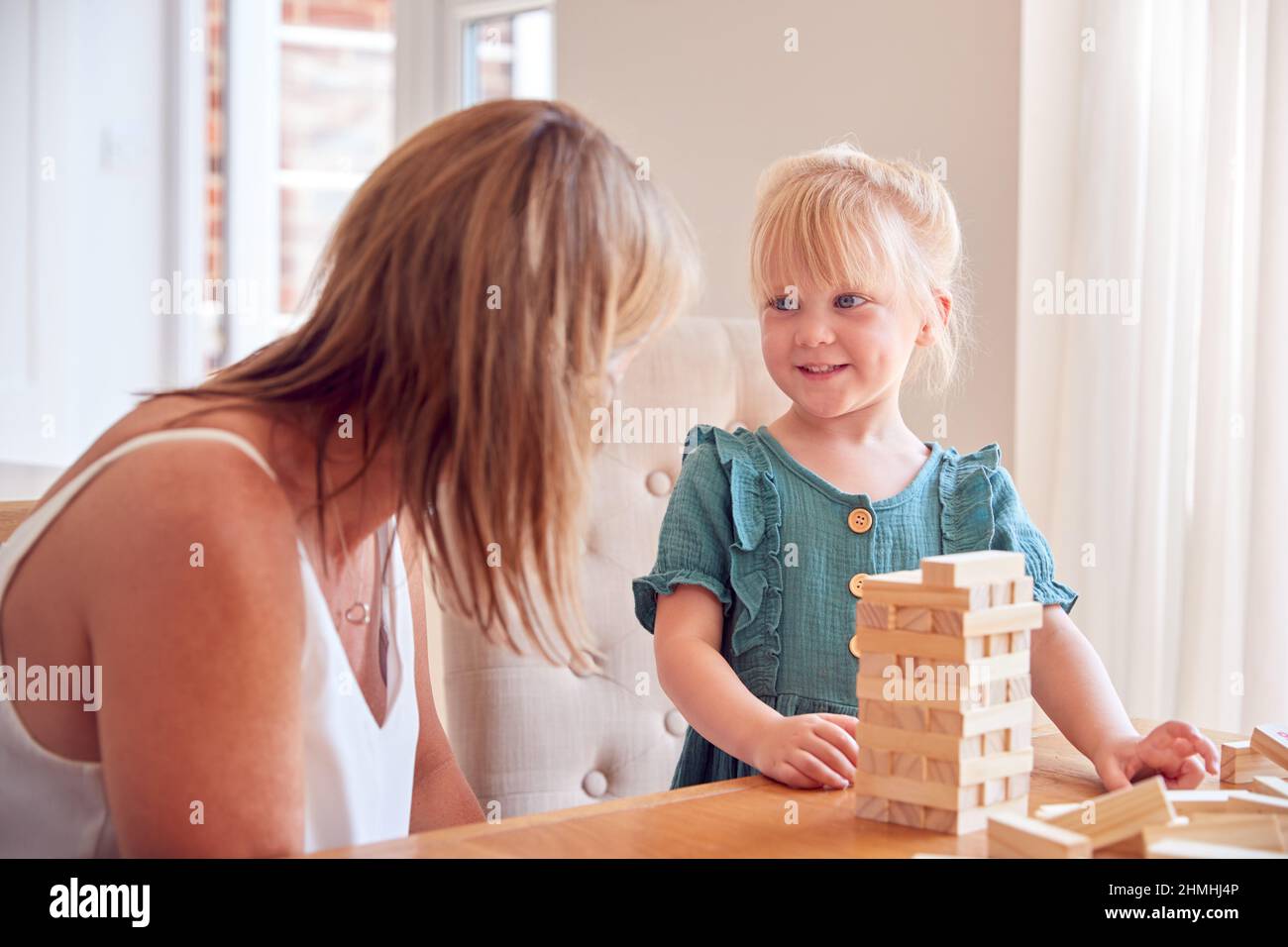 Mother And Daughter Having Fun Sitting At Table Playing Game Building Tower From Wooden Blocks ...