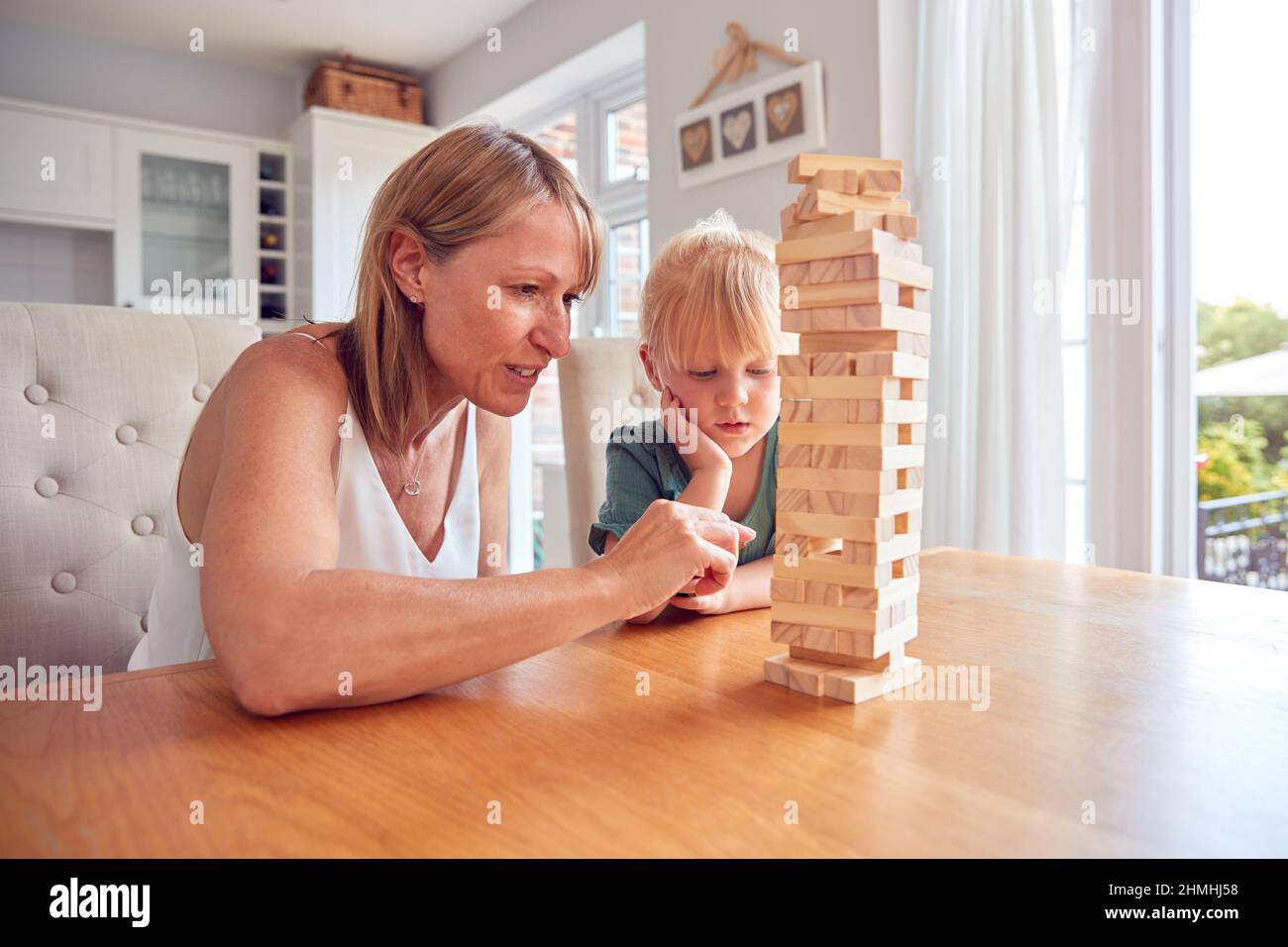 Mother And Daughter Having Fun Sitting At Table Playing Game Building Tower From Wooden Blocks ...