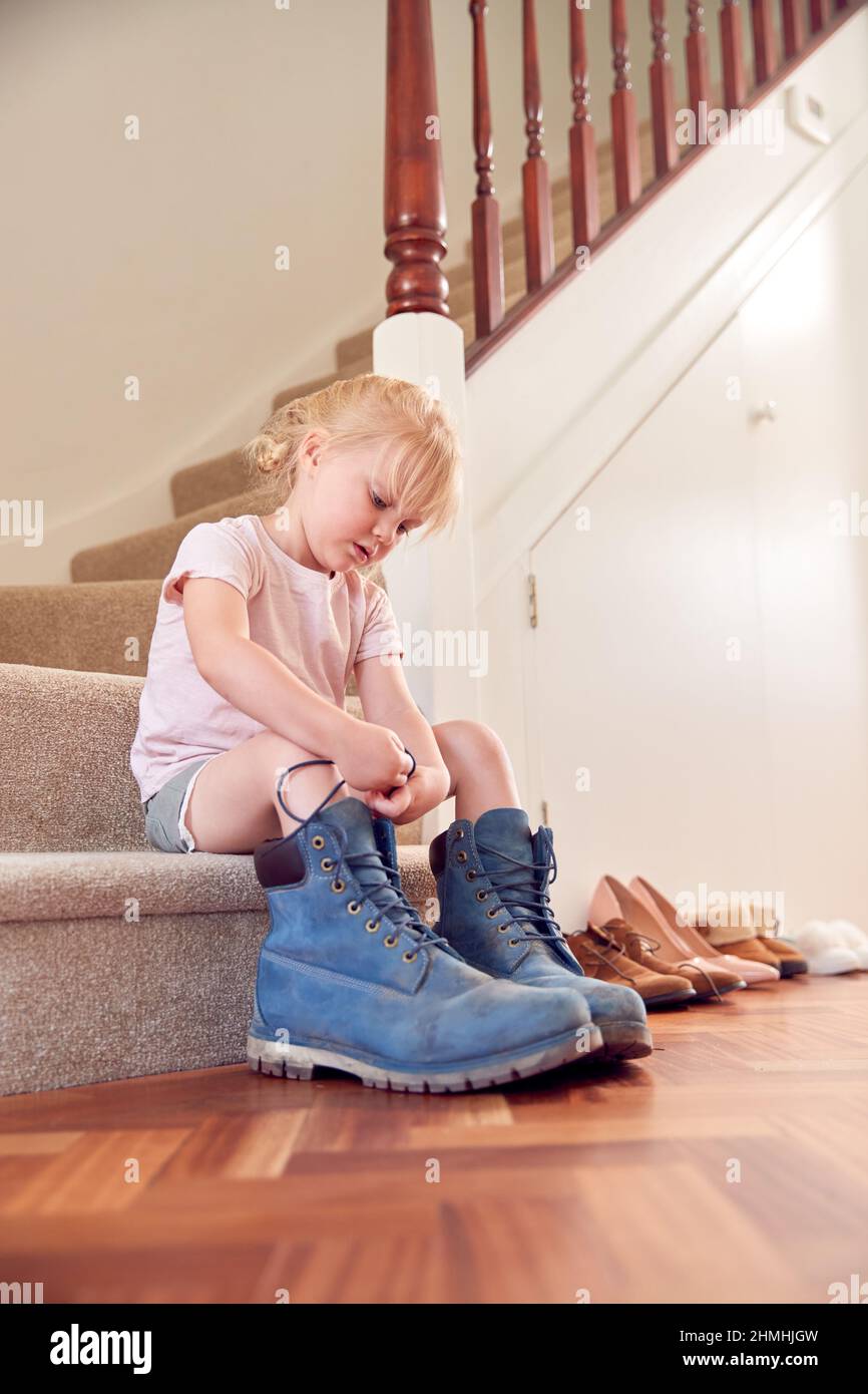 Young Girl Sitting On Stairs Dressing Up And Putting On Father's Work ...