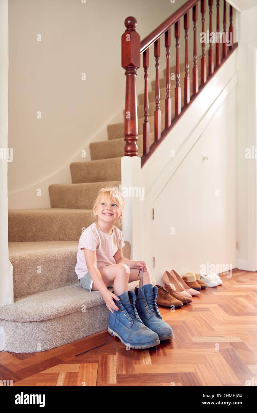 Young Girl Sitting On Stairs Dressing Up And Putting On Father's Work ...