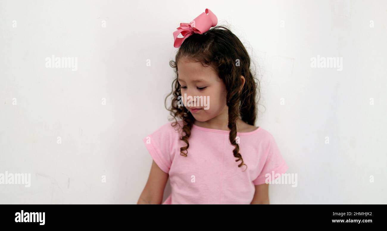 Shy little girl trying to dance on white wall, hispanic diverse shy ...