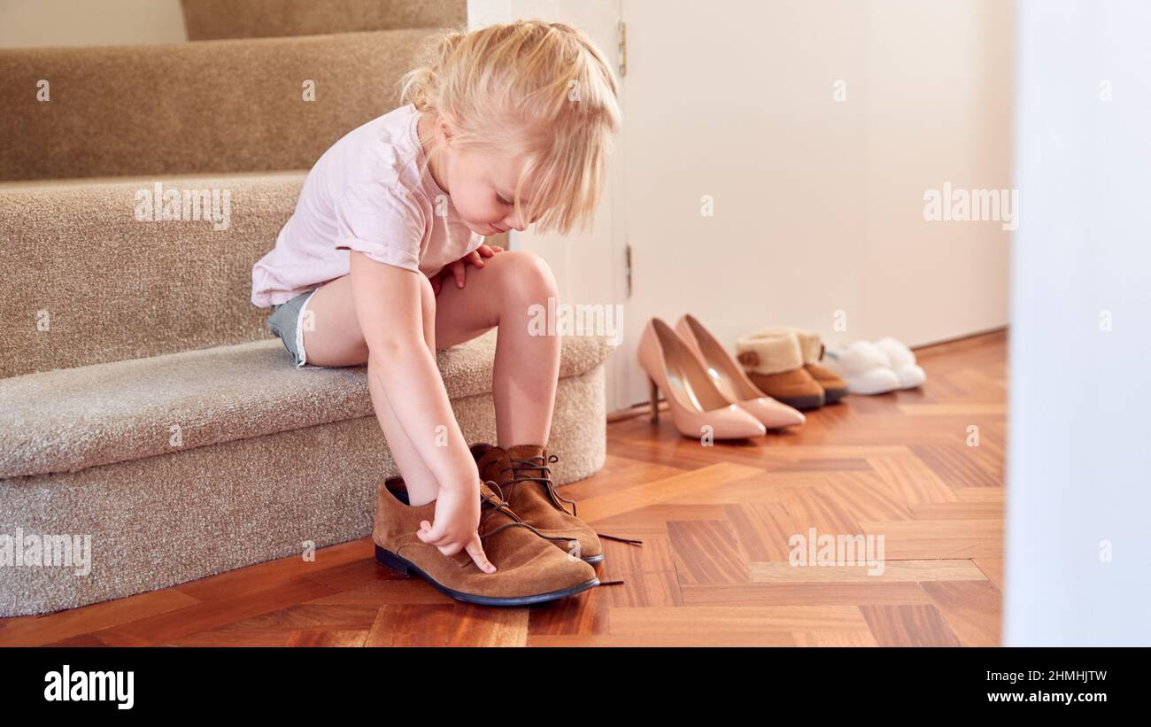 Young Girl Sitting On Stairs Dressing Up And Putting On Parent's Shoes ...