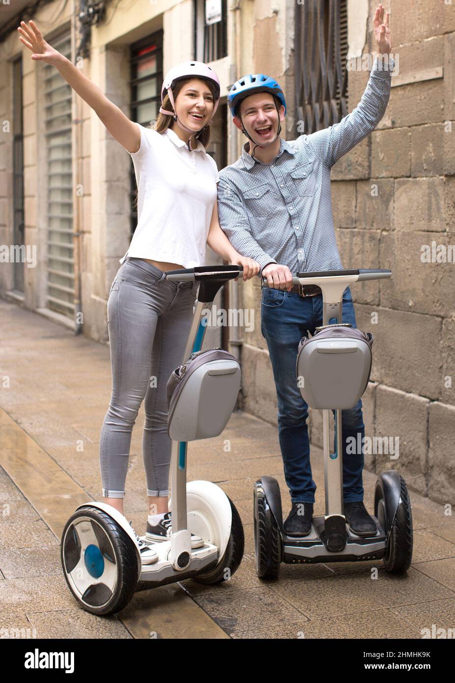 young couple guy and girl walking on segway in streets of european city ...