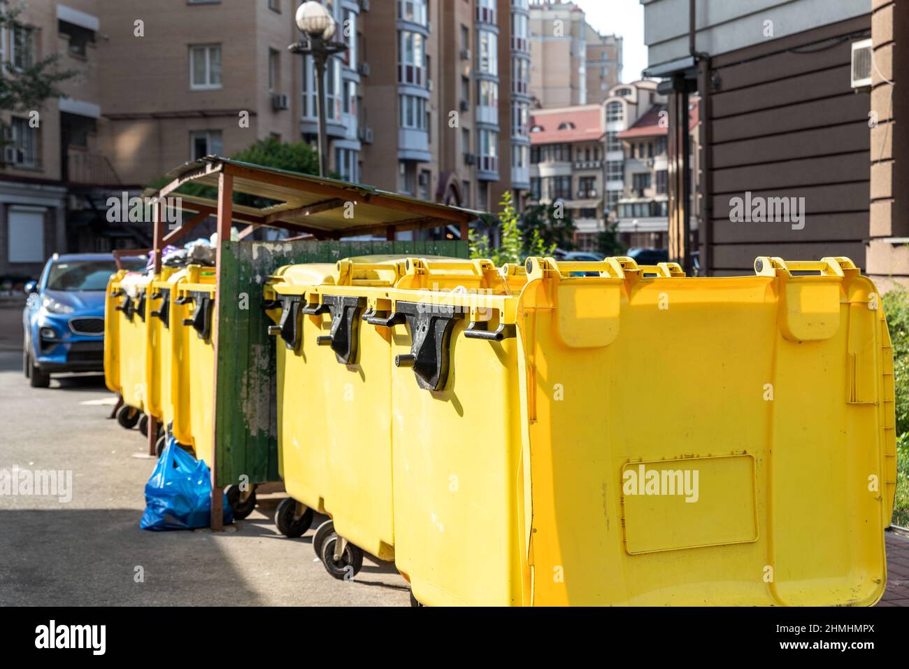 Rows of many big plastic yellow dumpster cans full of black plastic ...