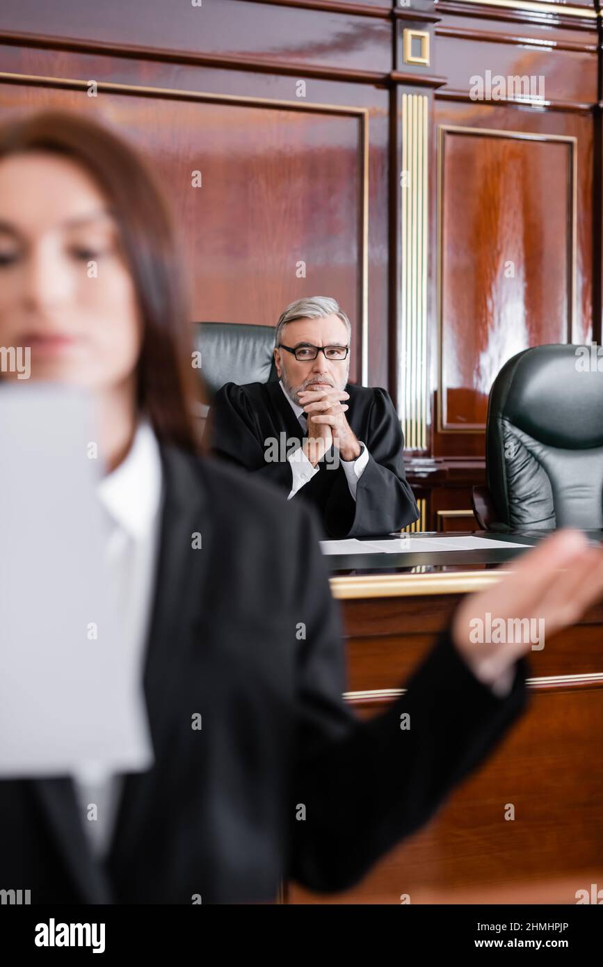 blurred prosecutor talking in court near judge sitting with clenched ...