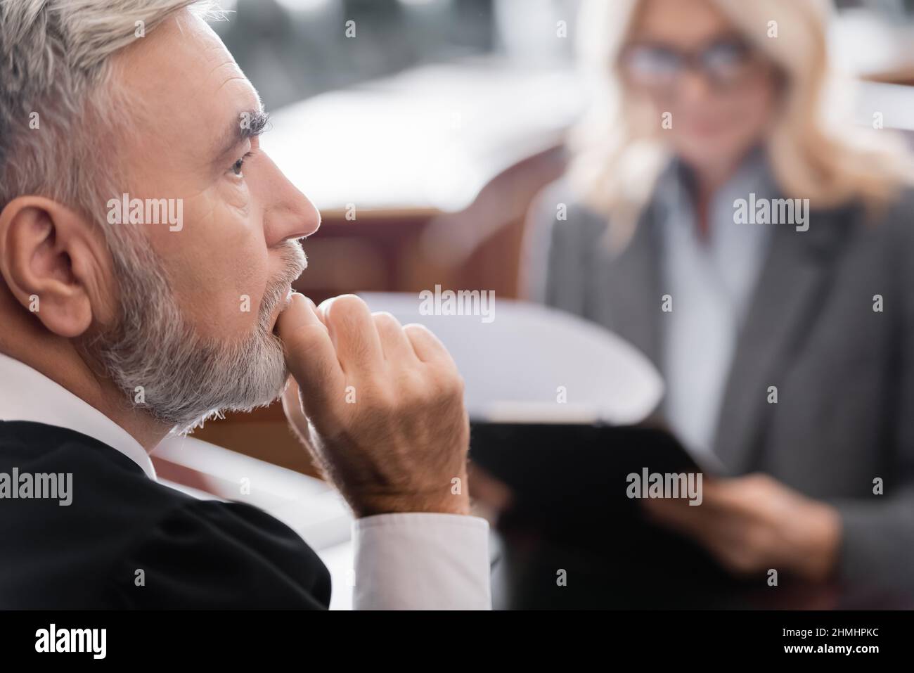selective focus of senior judge thinking near blurred attorney in ...