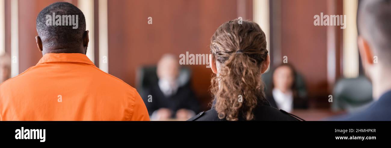 back view of accused african american man, bailiff and juryman in ...