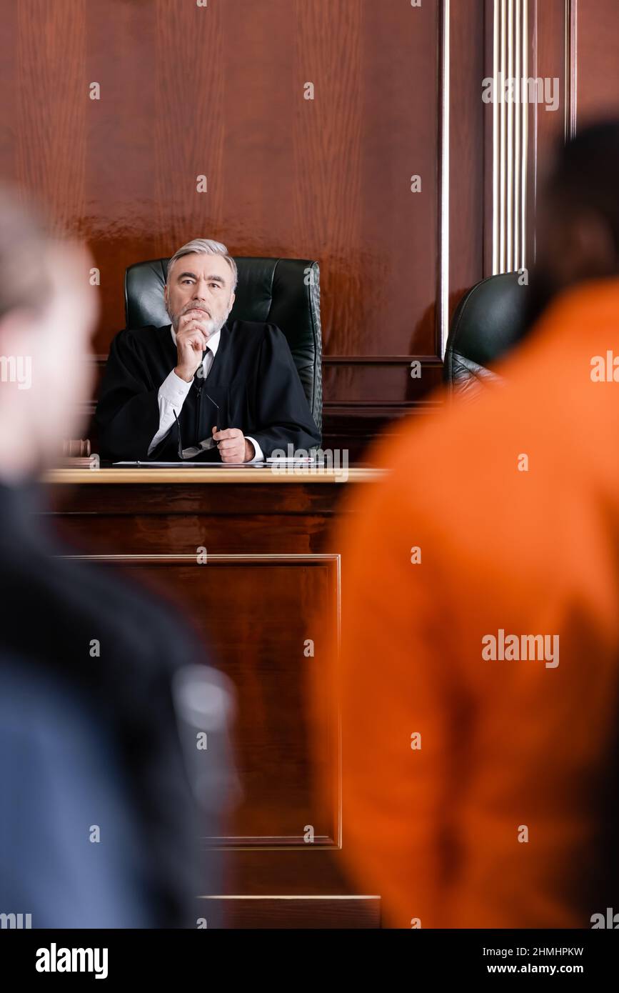 thoughtful judge looking at blurred african american man standing near ...