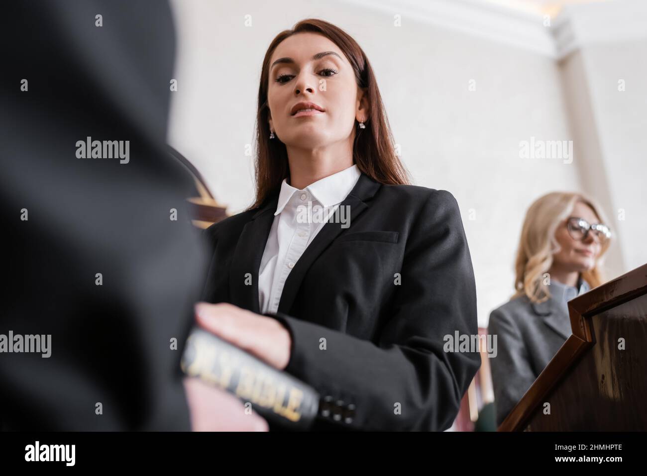 low angle view of brunette witness giving oath on bible in court Stock ...