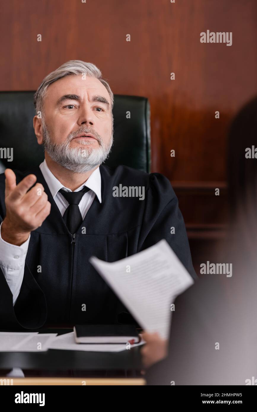 senior judge pointing with finger while talking to blurred prosecutor ...