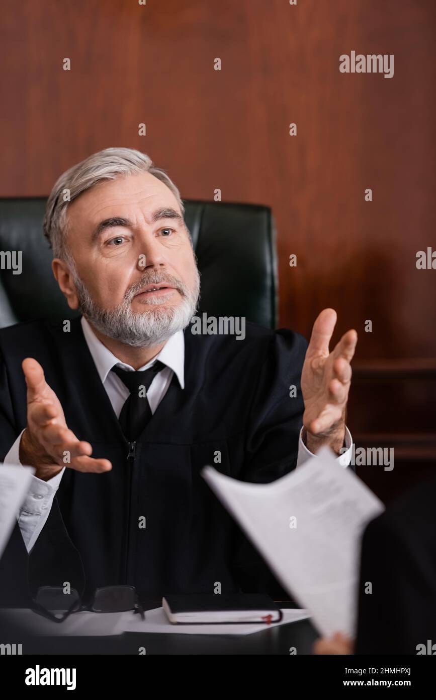 senior judge pointing with hands while talking to blurred prosecutor ...