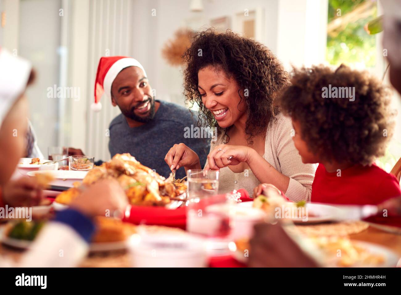 Family In Paper Hats Enjoying Eating Christmas Meal At Home Together ...
