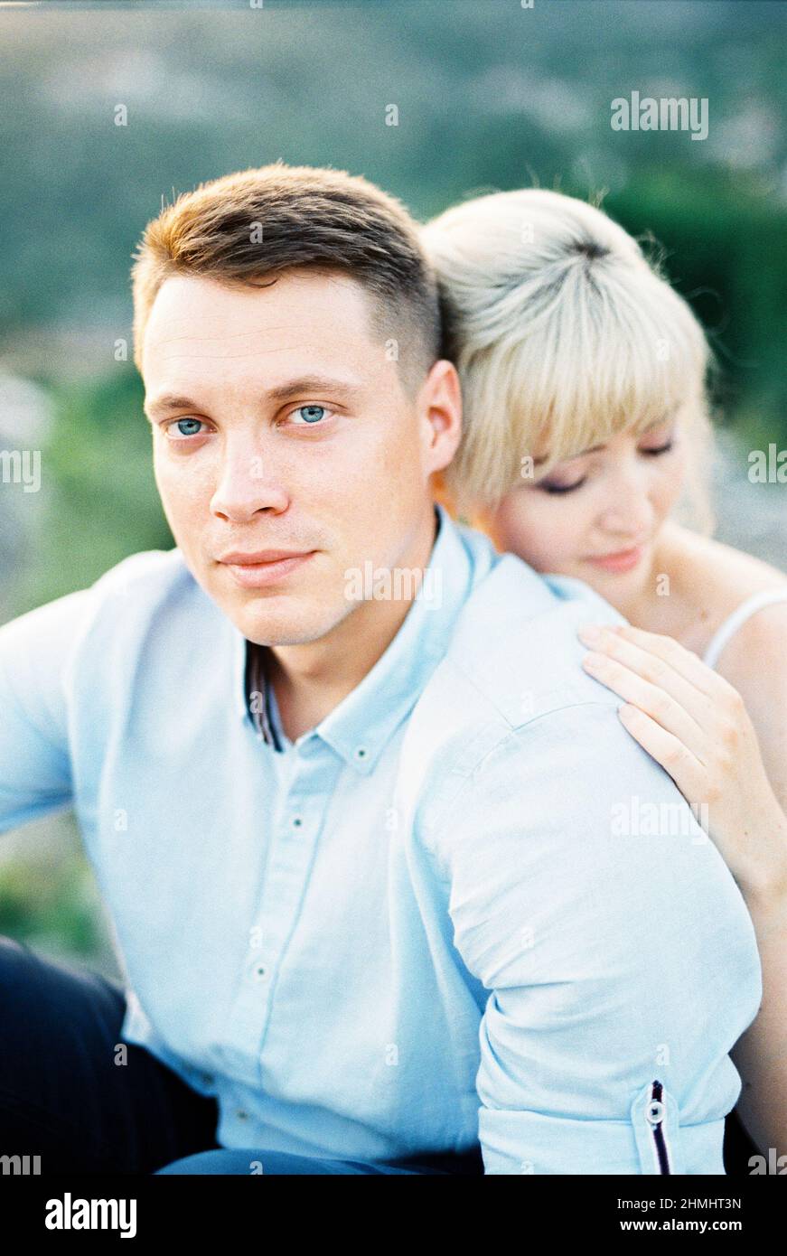 Woman hugs man from behind, resting her head on his shoulder. Portrait ...