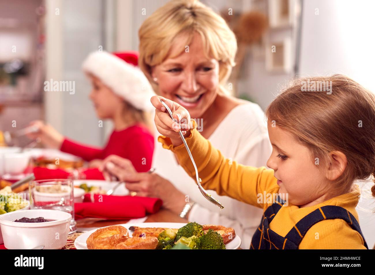 Multi Generation Family In Santa Hats Enjoying Eating Christmas Meal At ...