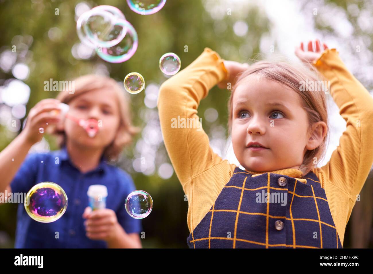 Boy And Girl Having Fun In Garden Blowing Bubbles Together Stock Photo ...