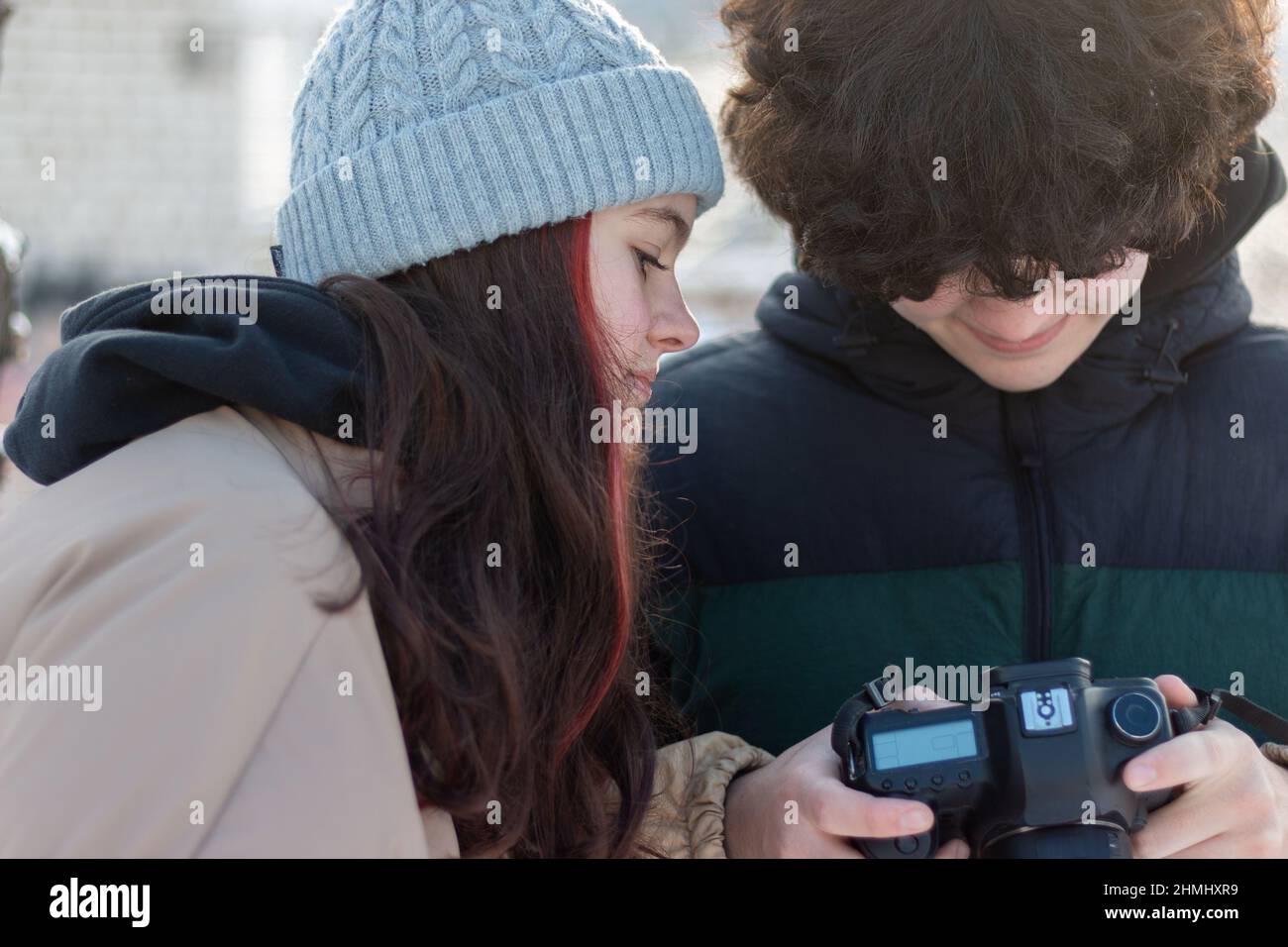 Teenagers in winter clothes look at the DSLR camera screen while ...