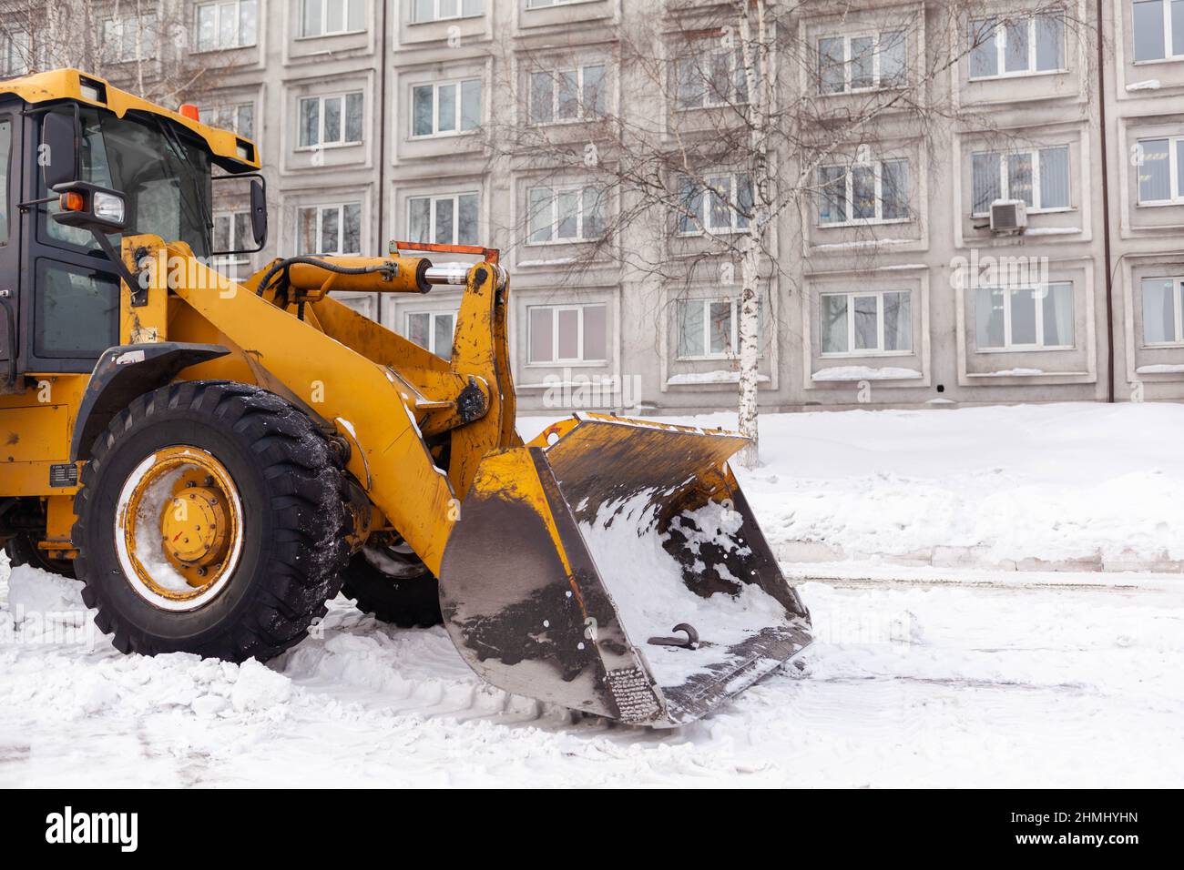 Big orange tractor cleans up snow from the road and loads it into the ...