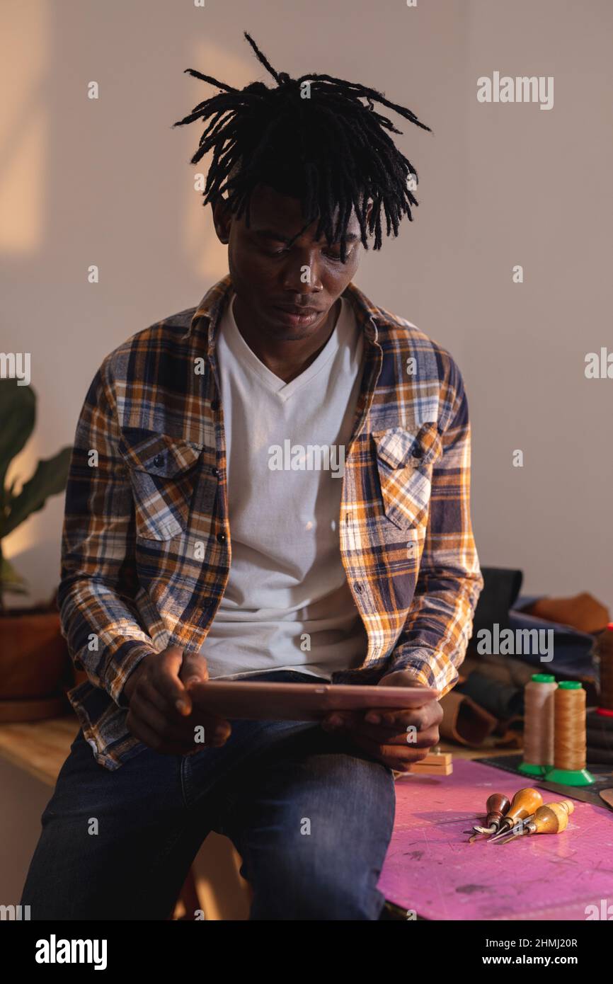 African american young craftsman using digital tablet while sitting ...