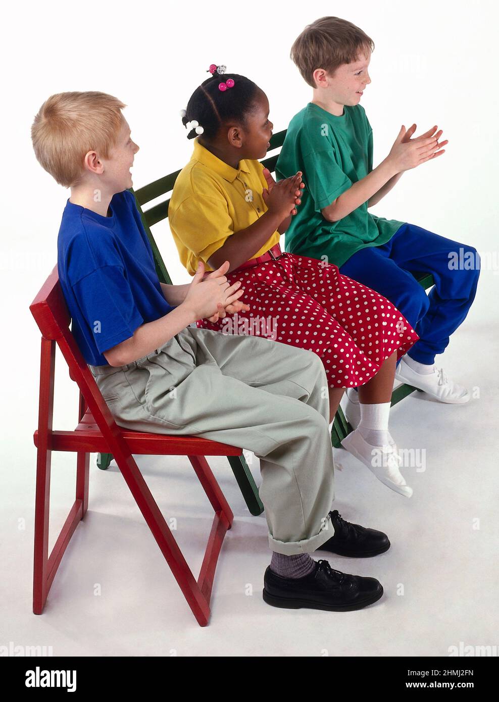 Three children sitting down applauding as if watching a magic show ...