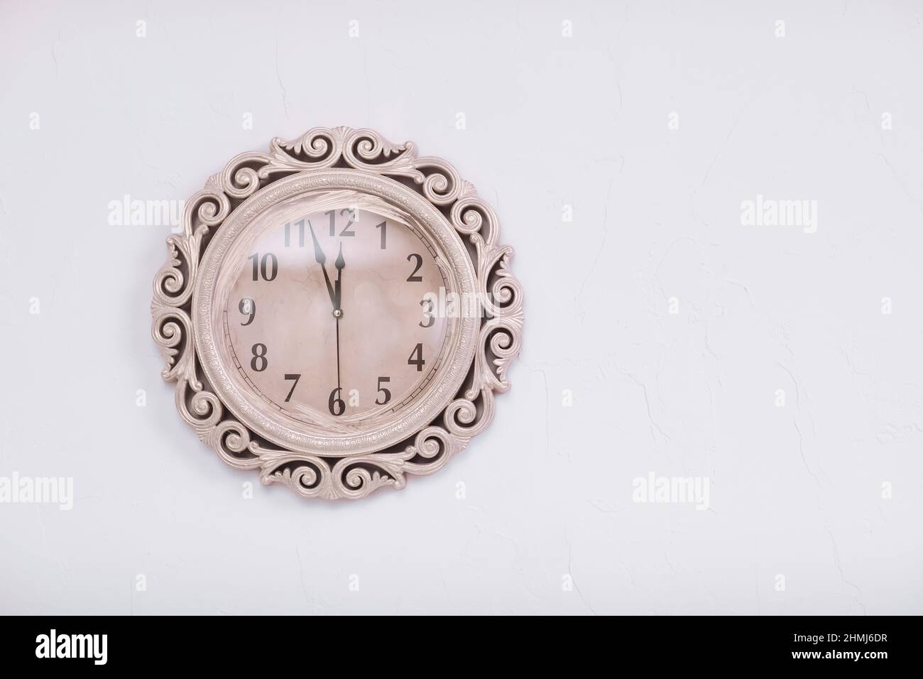 classic clock on a white wall background. almost twelve o'clock. eleven ...