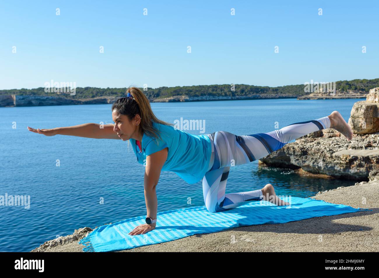 middle-aged fitness woman outdoors in front of the sea does yoga ...