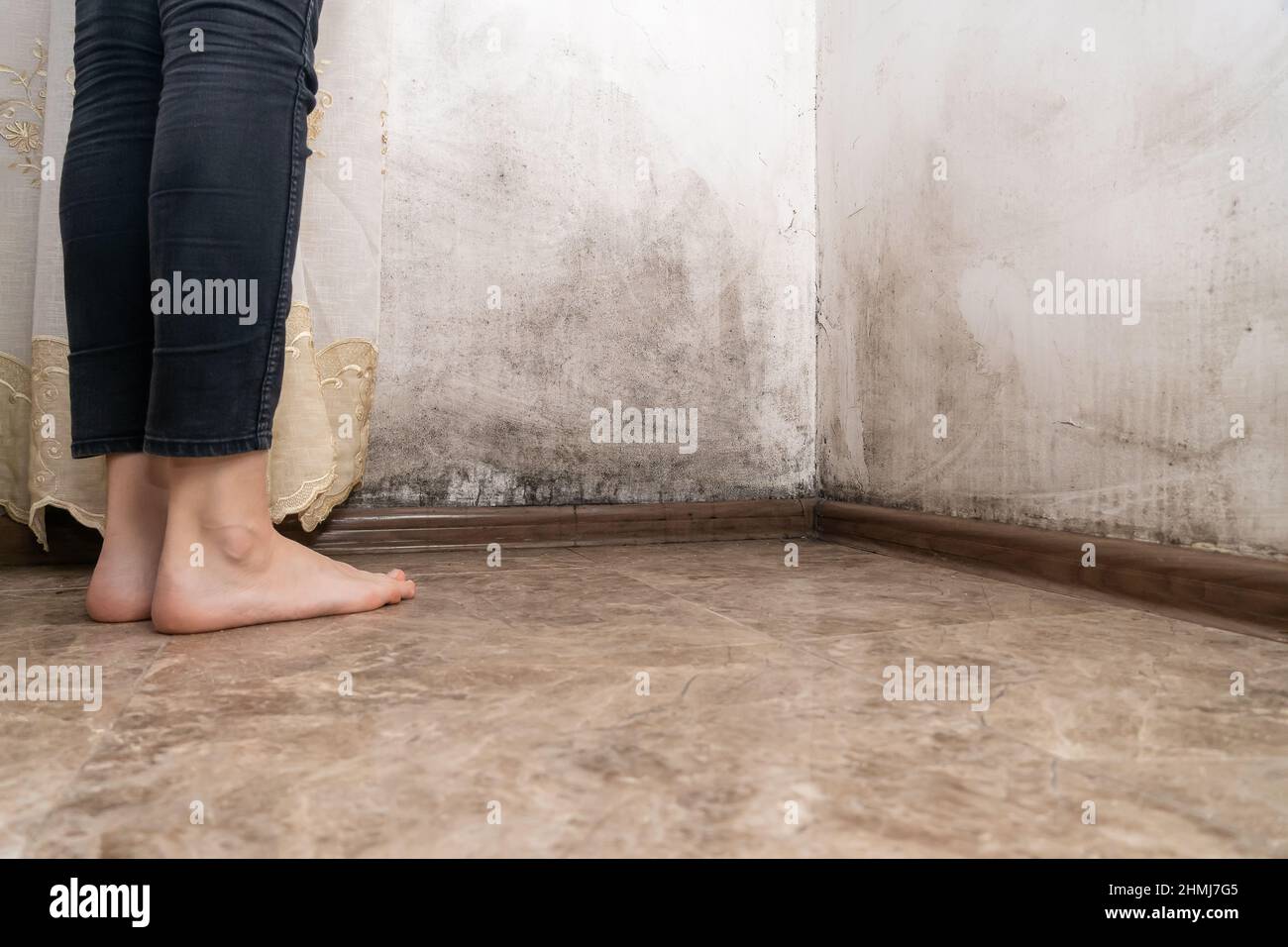 Close-up of a woman's legs standing near a white wall with mold Stock ...