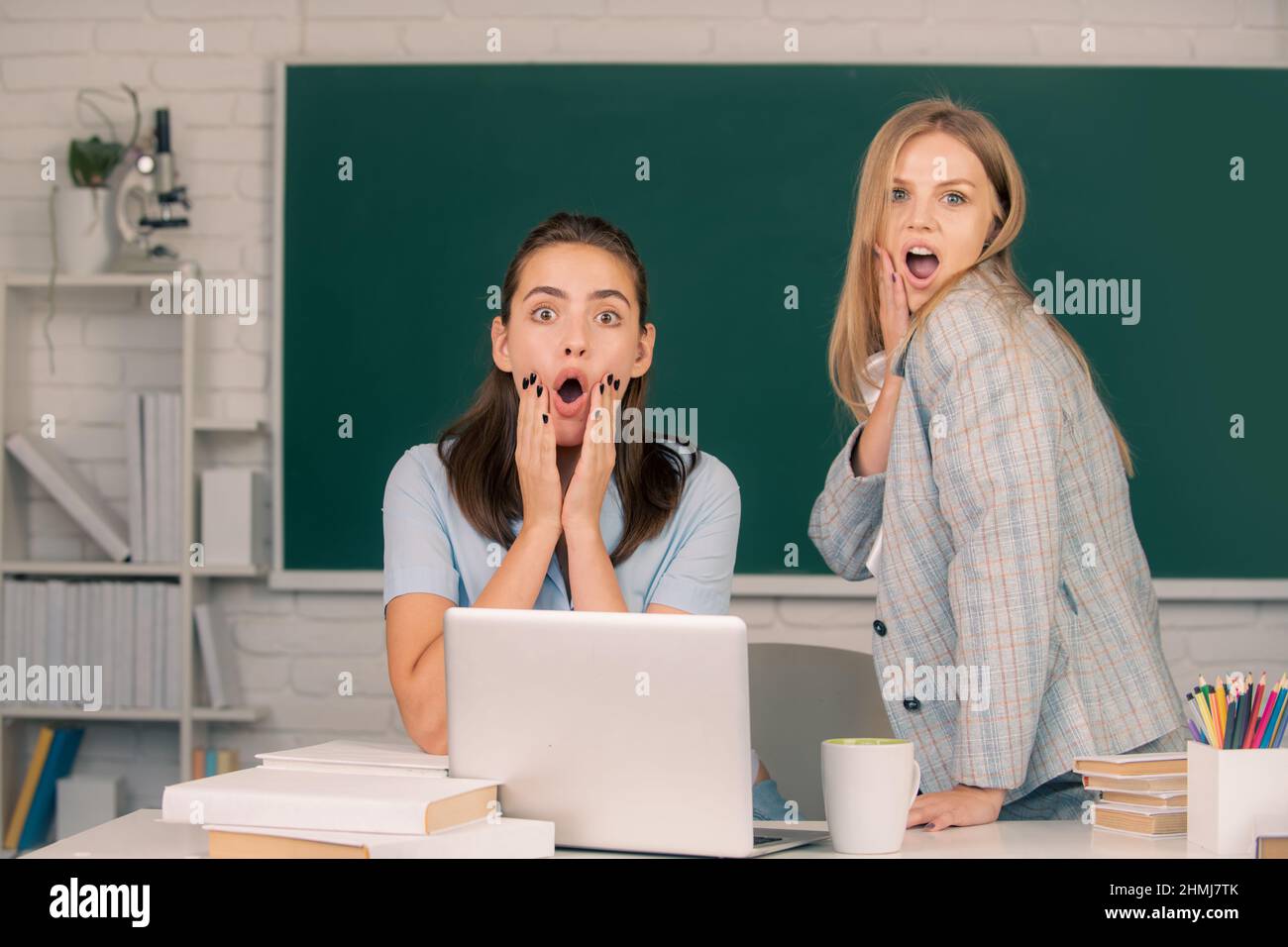 Two surprised students girls friends in classroom at school college or ...