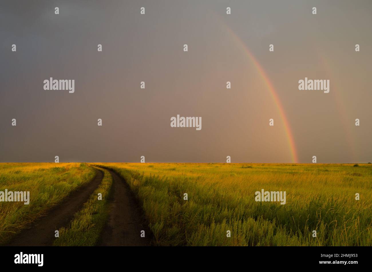 Double rainbow after rain on the background of storm clouds.Road in the ...