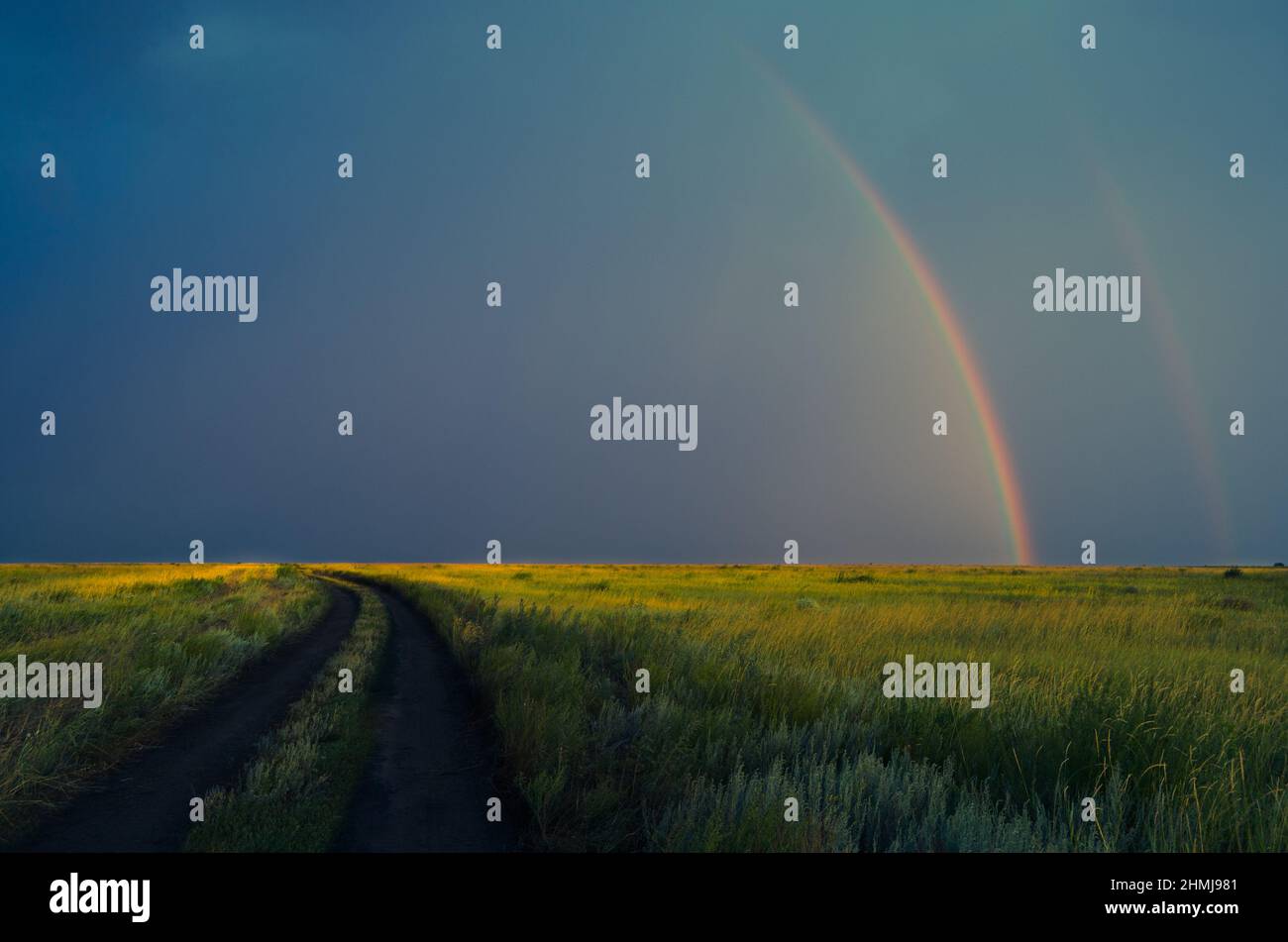 Double rainbow after rain on the background of storm clouds.Road in the ...