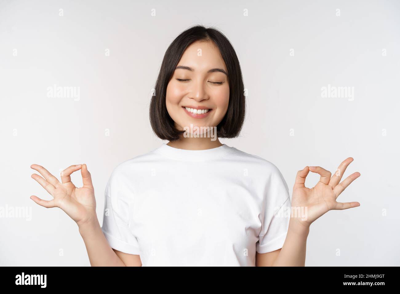 Portrait of young asian woman meditating, smiling pleased and practice ...