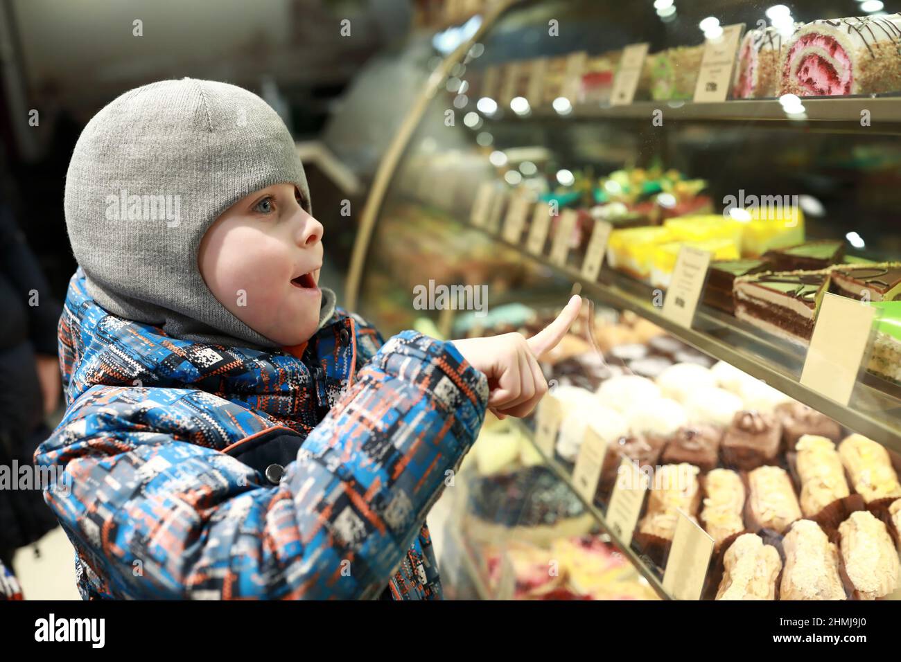 Portrait of child choosing cake in cafe showcase Stock Photo - Alamy