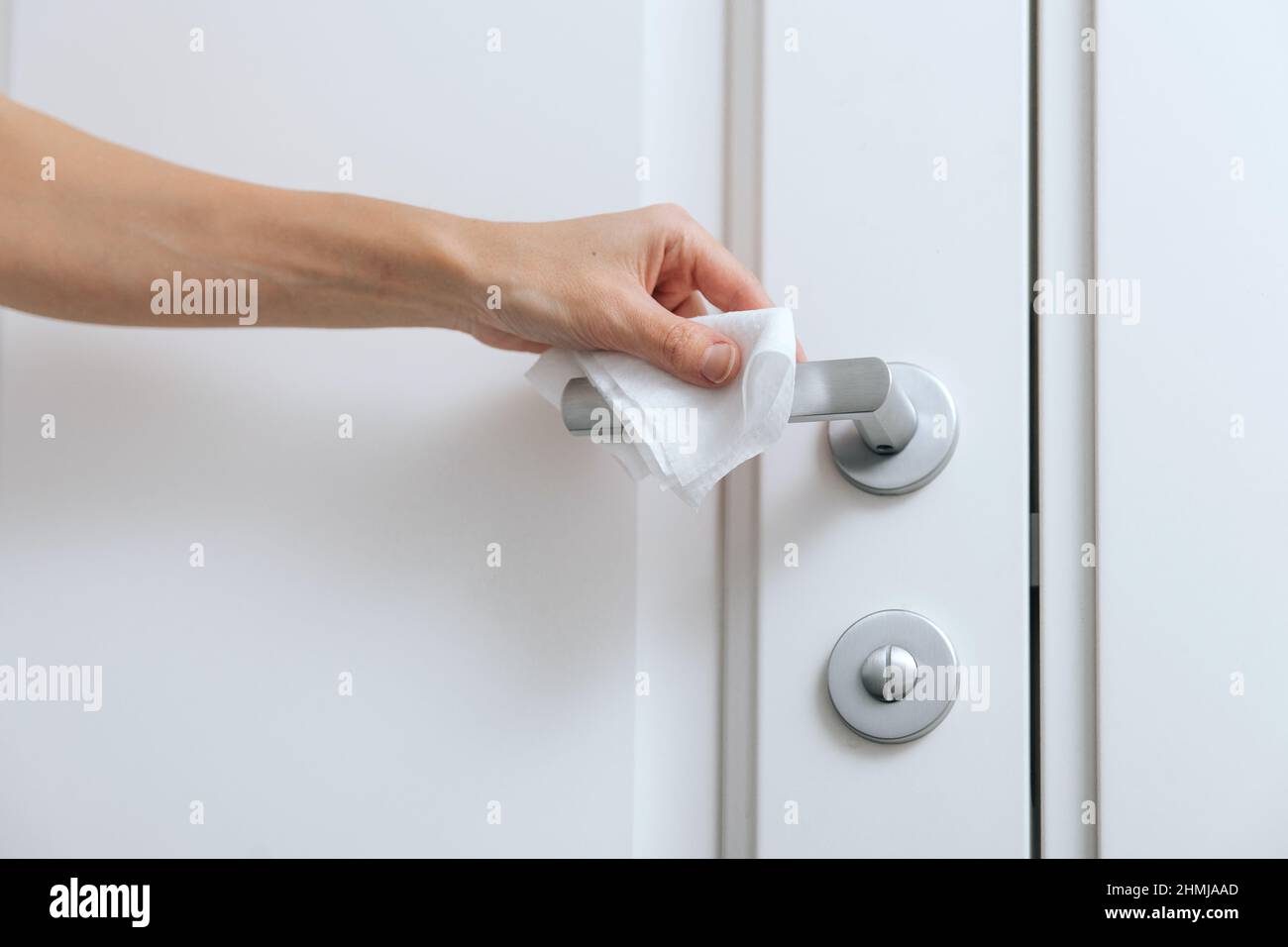Cleaning door handles with an antiseptic wet wipe and gloves. Woman ...