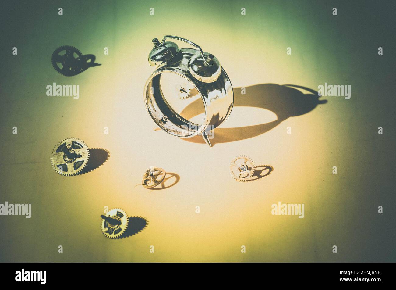 Disassembled alarm clock and scattered gears in bright light with hard ...