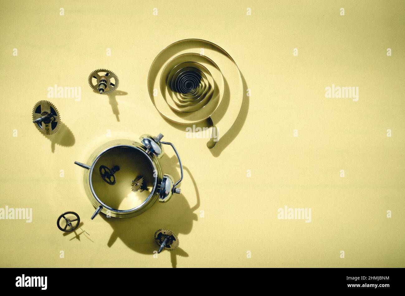 Old alarm clock disassembled into gears on a bright yellow background ...