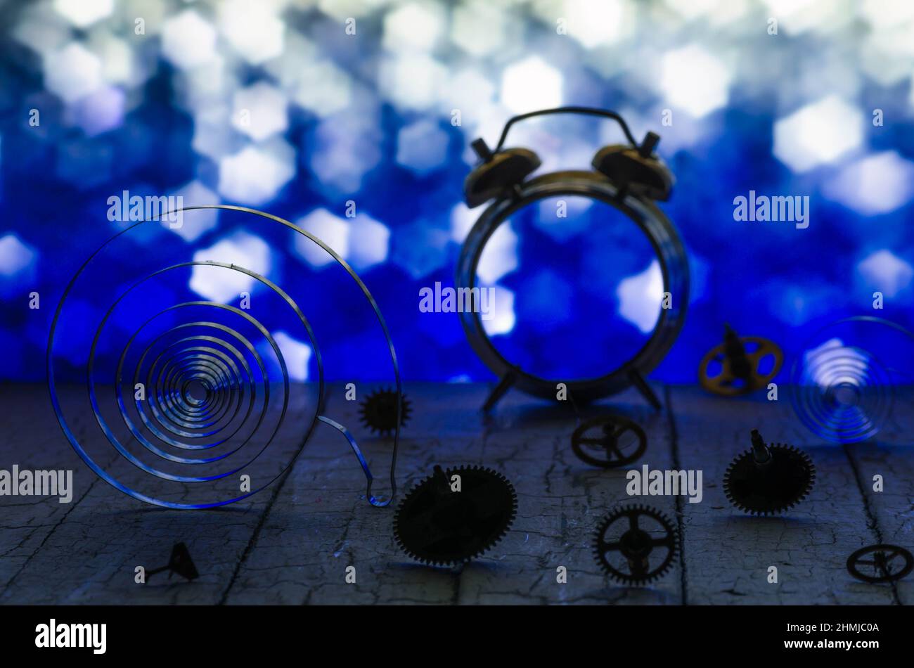 Broken alarm clock with springs and gears scattered on the background ...