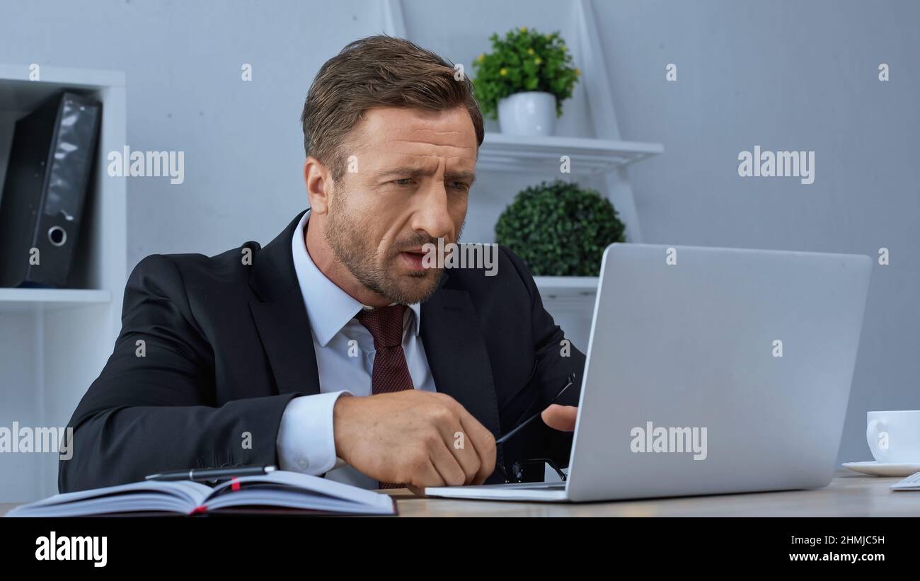 thoughtful businessman looking at laptop while working in office Stock ...