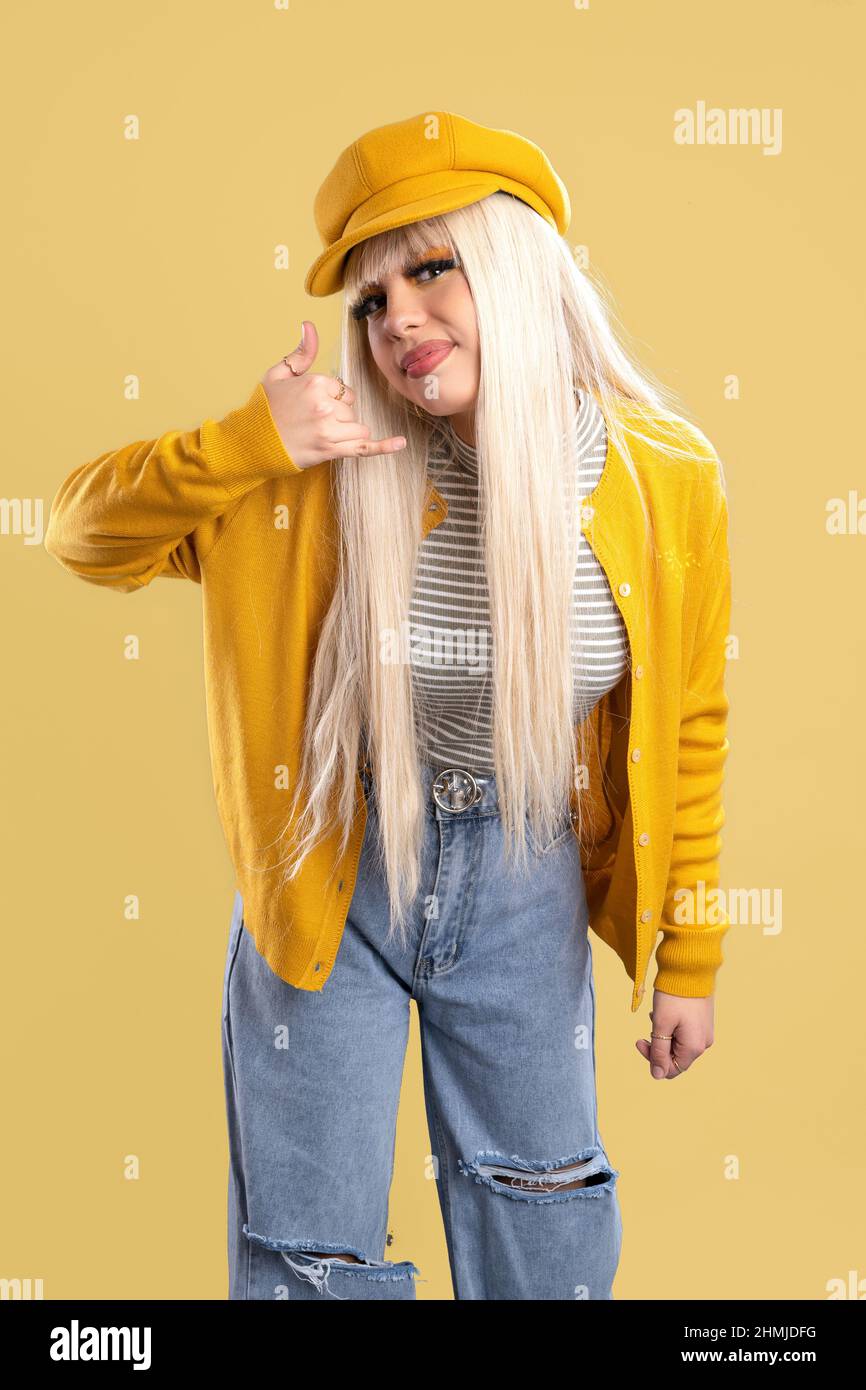 Blond caucasian woman with yellow cap making a gesture of calling by ...