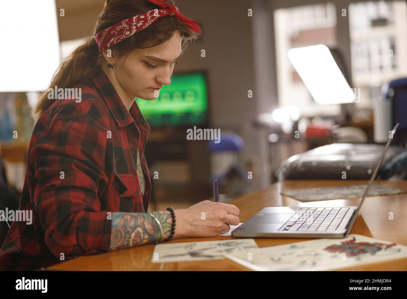 Focused tattoo artist in red shirt drawing new sketch Stock Photo - Alamy