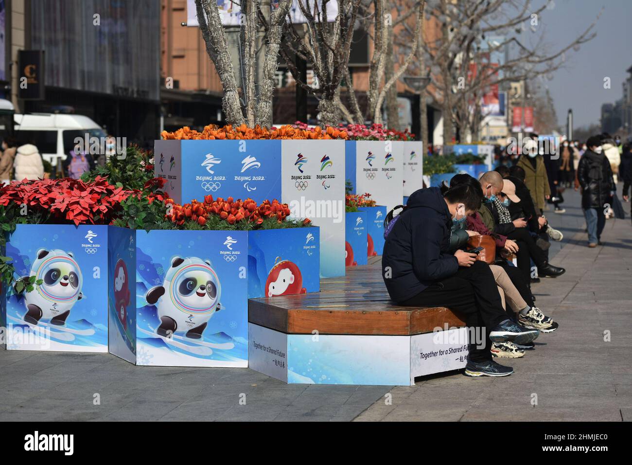 Beijing, China. 10th Feb, 2022. People sit near posters of "Bing Dwen Dwen" and "Shuey Rhon Rhon ...