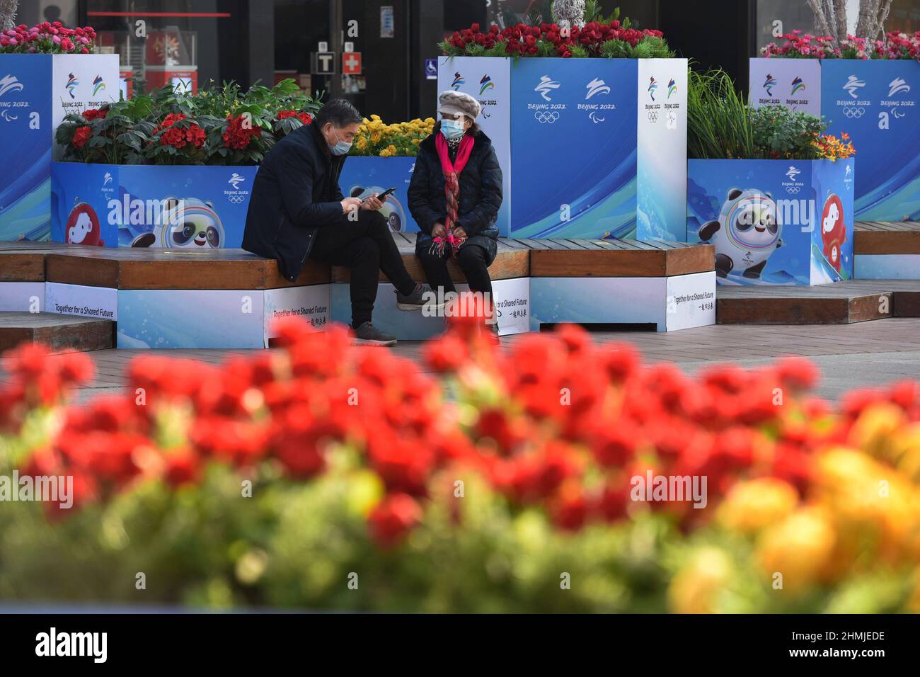 Beijing, China. 10th Feb, 2022. People sit near posters of "Bing Dwen Dwen" and "Shuey Rhon Rhon ...