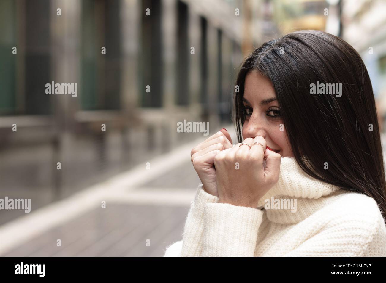 Young girl on the street in winter holding the collar of her sweater ...