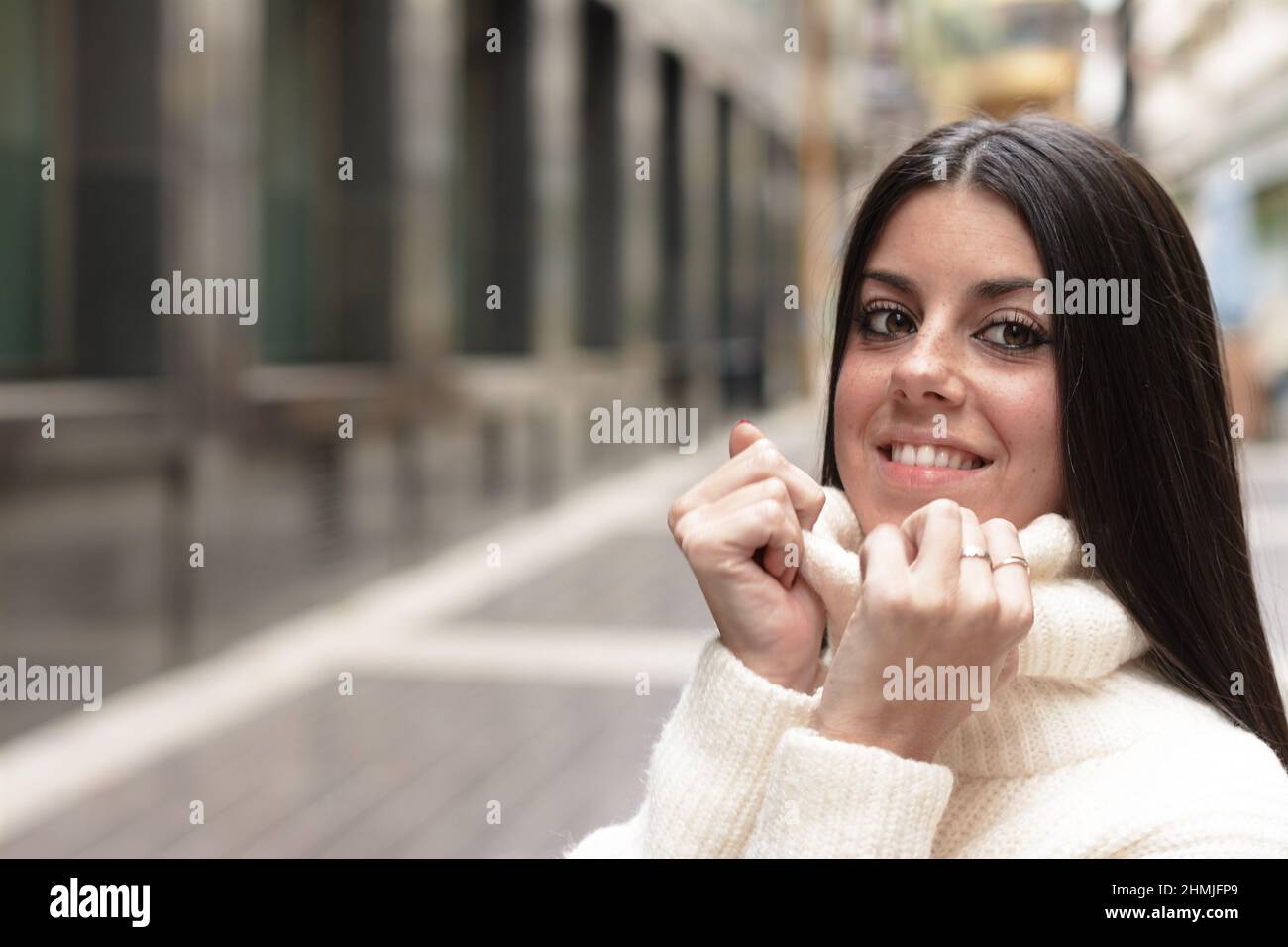 Young girl on the street in winter holding the collar of her sweater ...