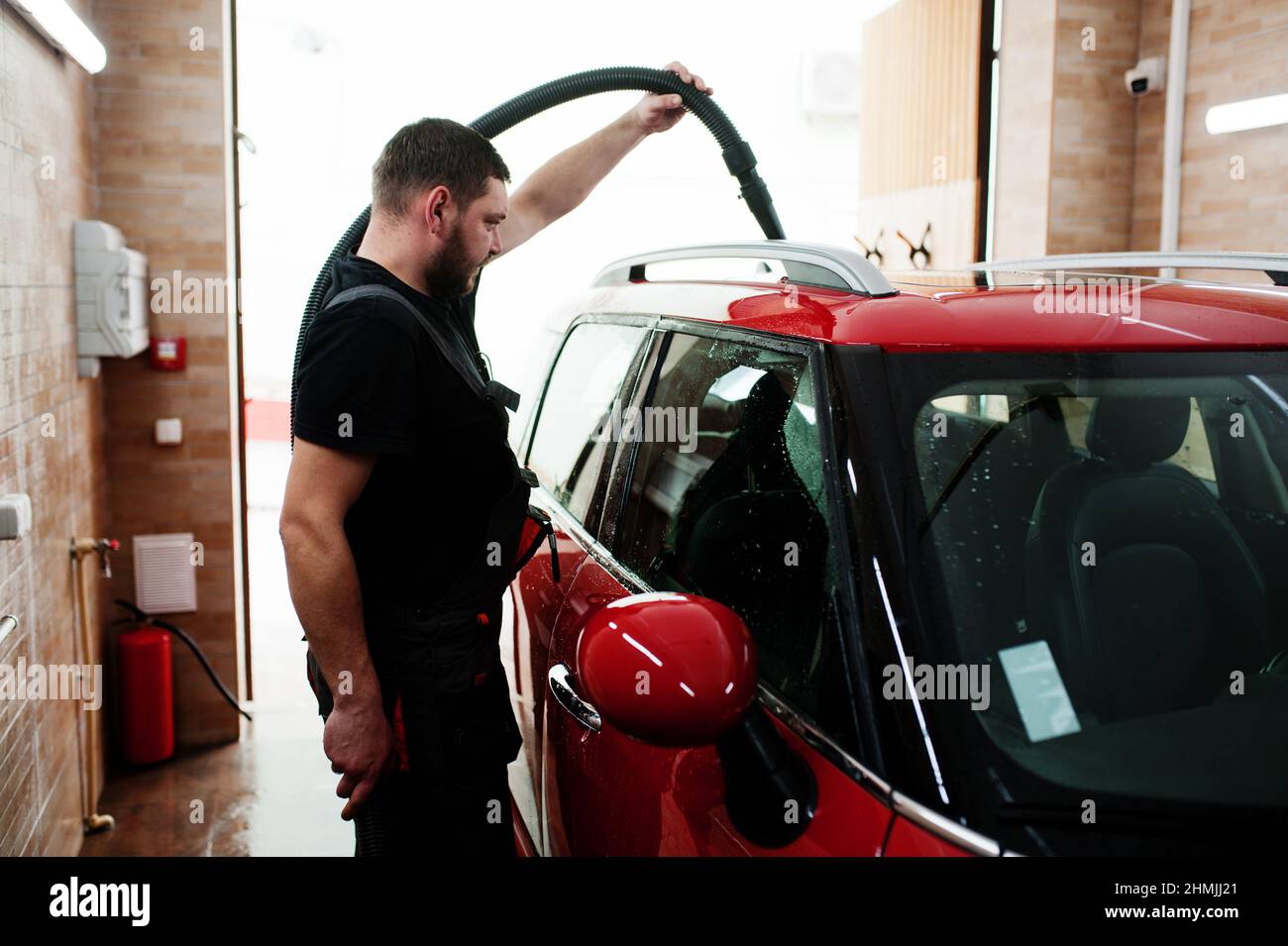 Man worker drying red car in detailing garage after washing Stock Photo ...